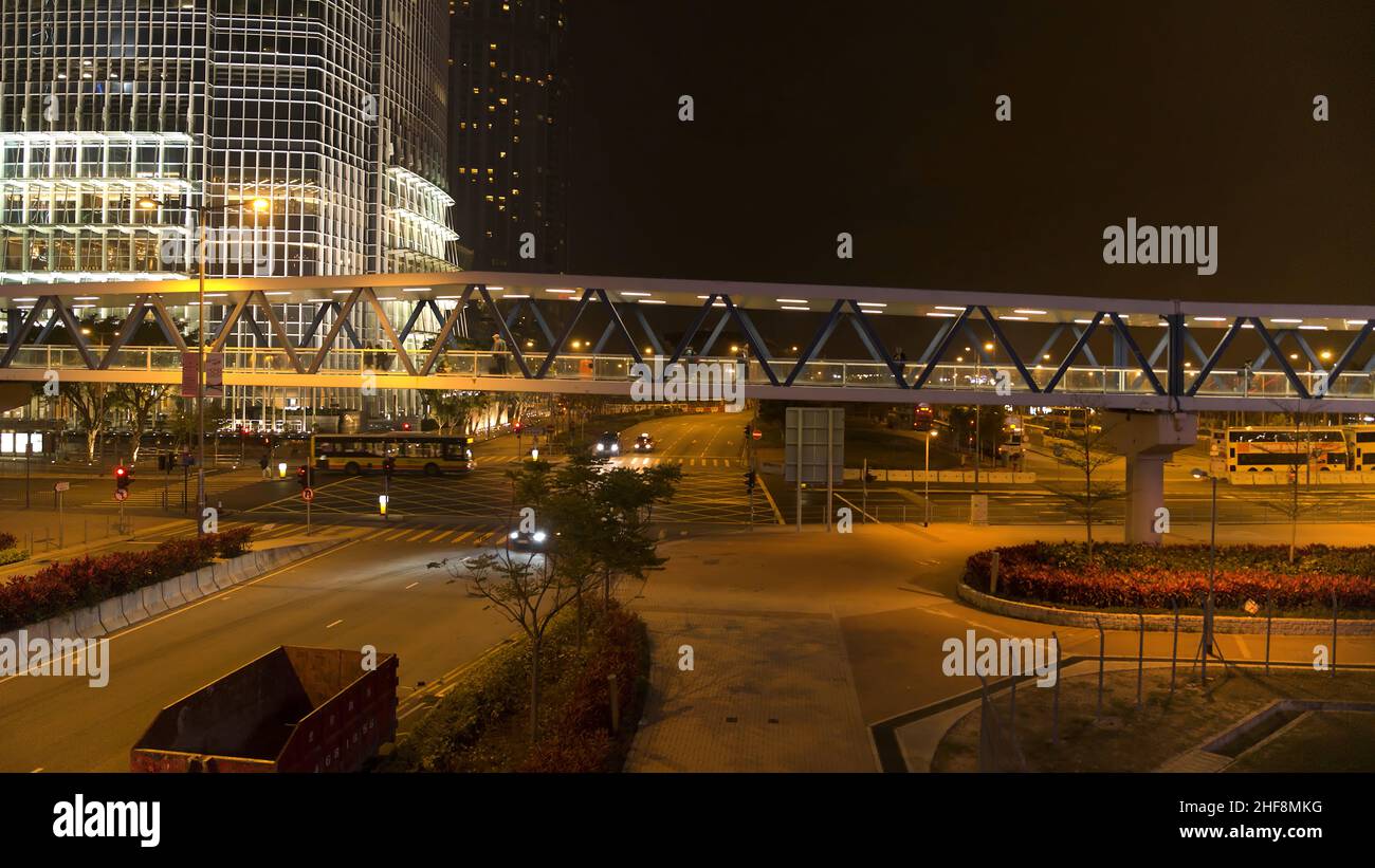 Footbridge with passersby above the road on night city background ...