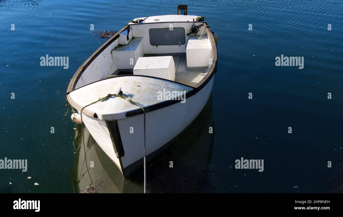 Small boats moored in a Cornish harbour, bright blue water with ...