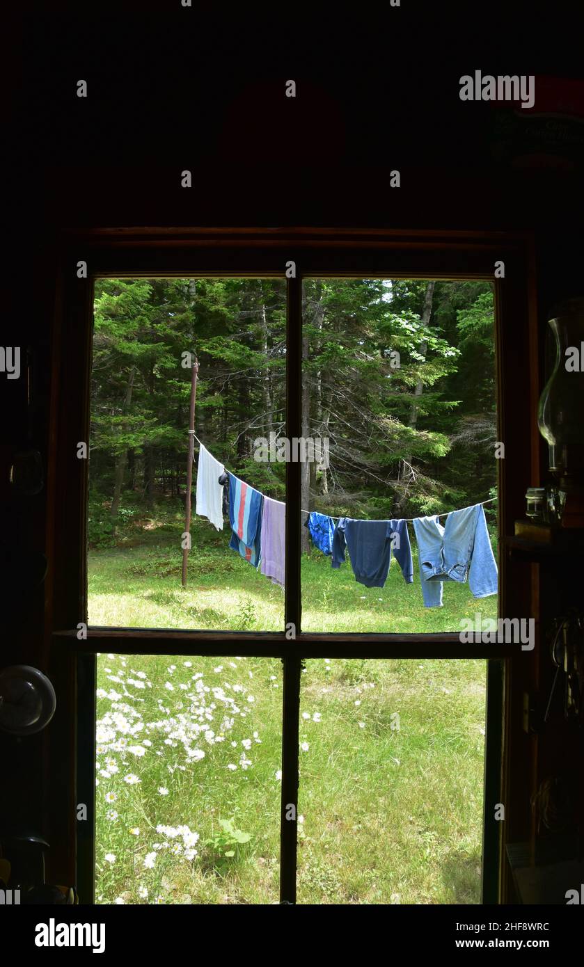 Peering out a cabin window at freshly washed clothing on a clothesline ...