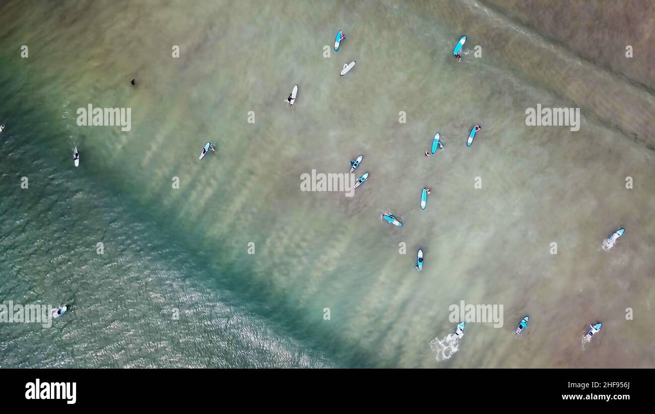 Aerial view of Surfer swimming on board near huge blue ocean wave ...