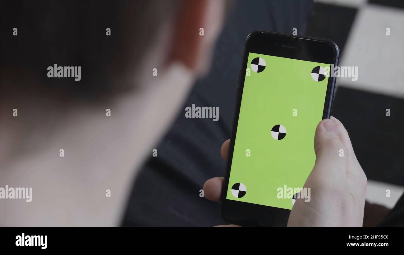 Man hands using mobile smartphone with green screen, over the shoulder ...