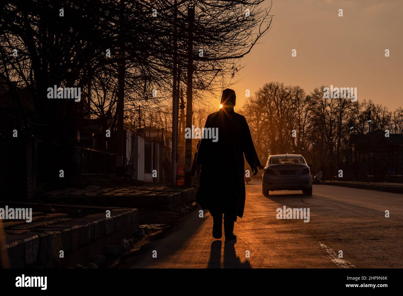 A silhouette of a man walking along the road during sunset. (Photo by ...