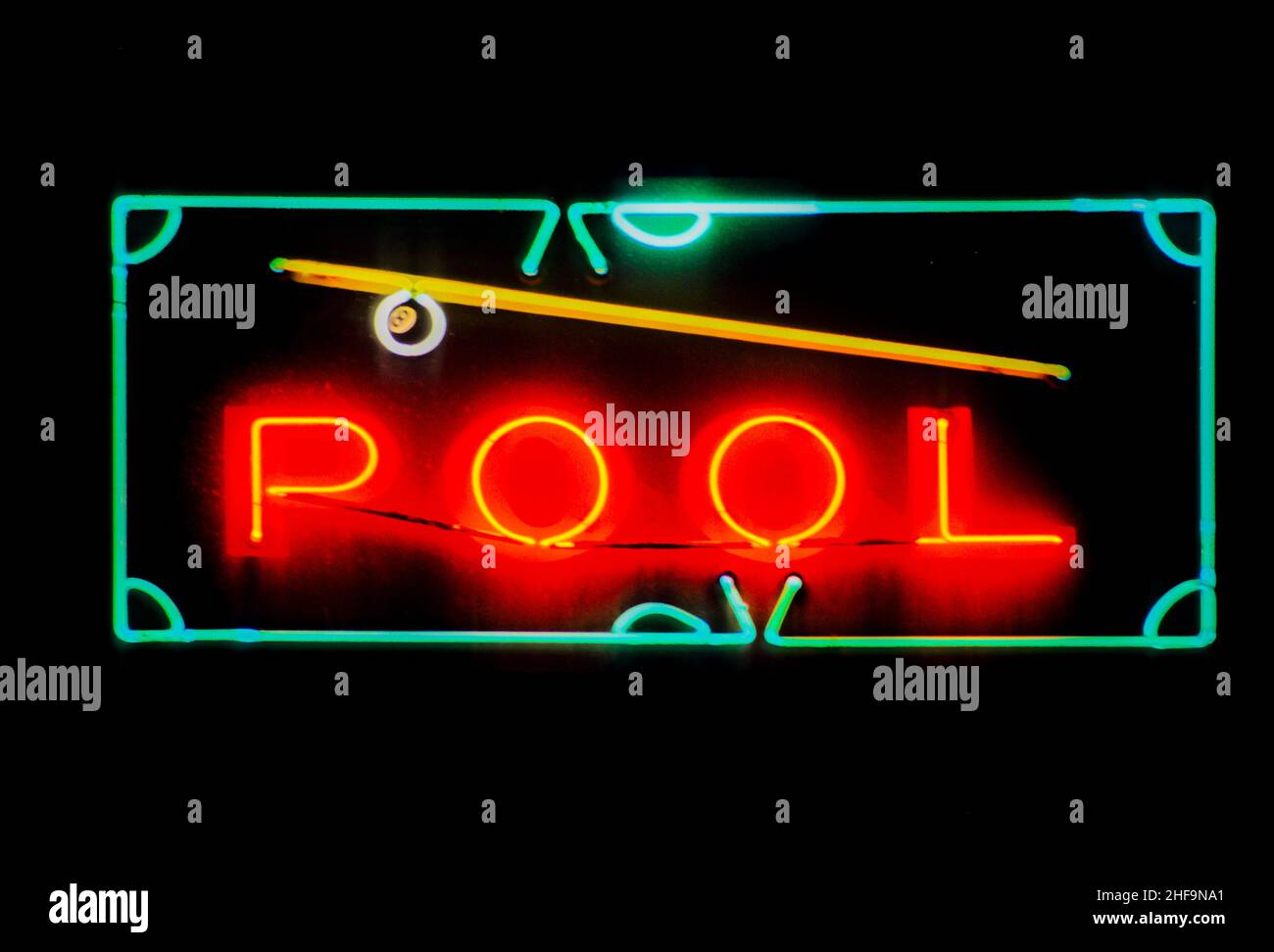 A neon sign including an eight-ball and a cue stick shines at night ...
