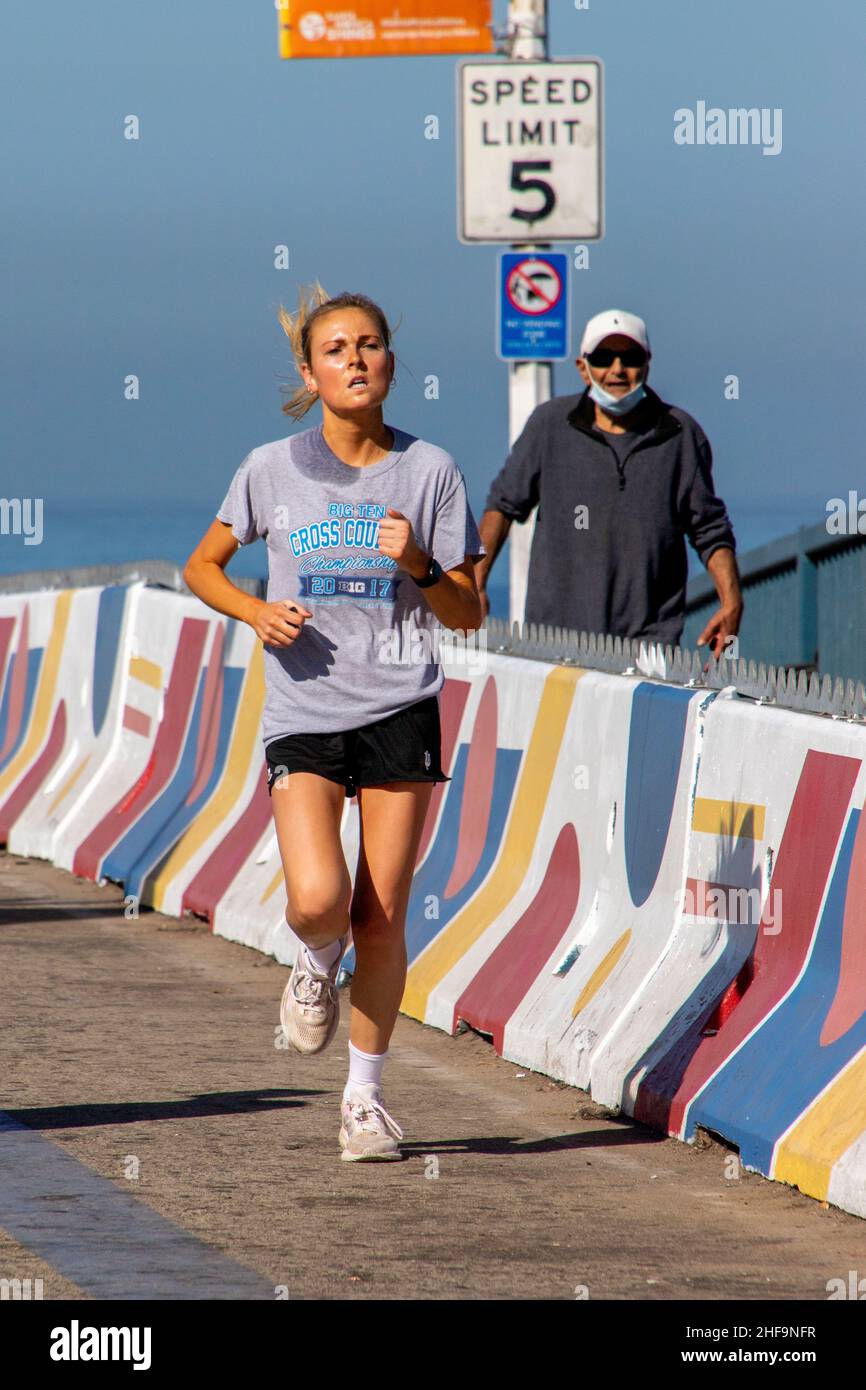 A sweating female runner passes a pedestrian behind a decorated traffic ...
