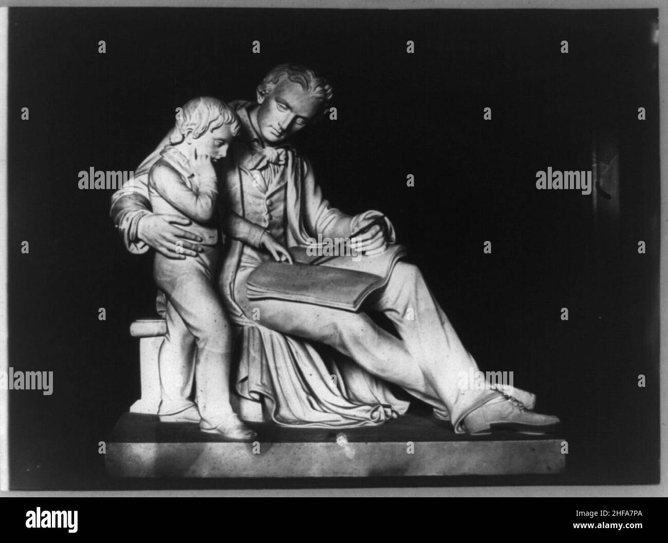 Sculpture of man and boy reading book Stock Photo - Alamy