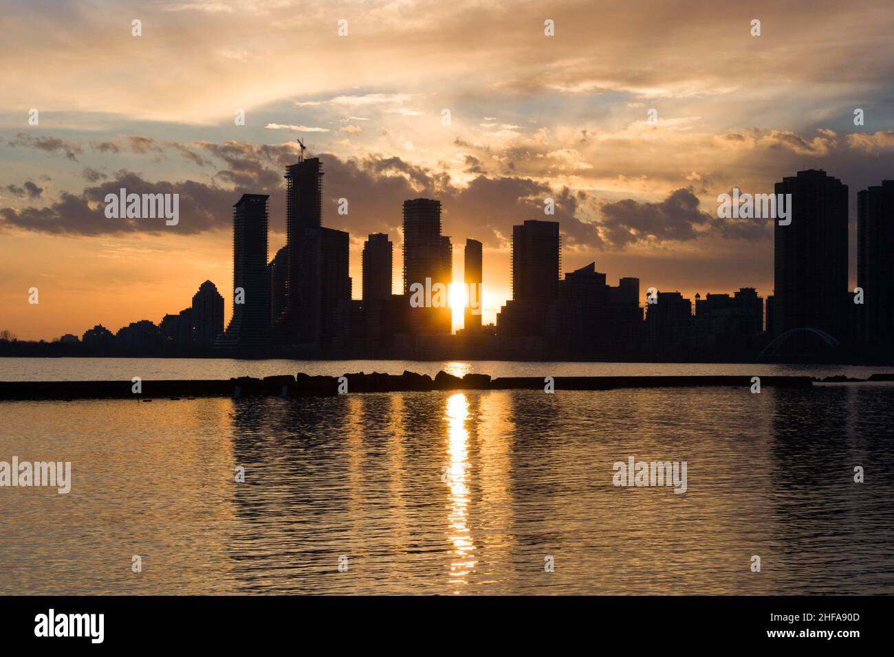 Amazing sunset over sityscape. Cloudy sky with sun rays, lake water ...