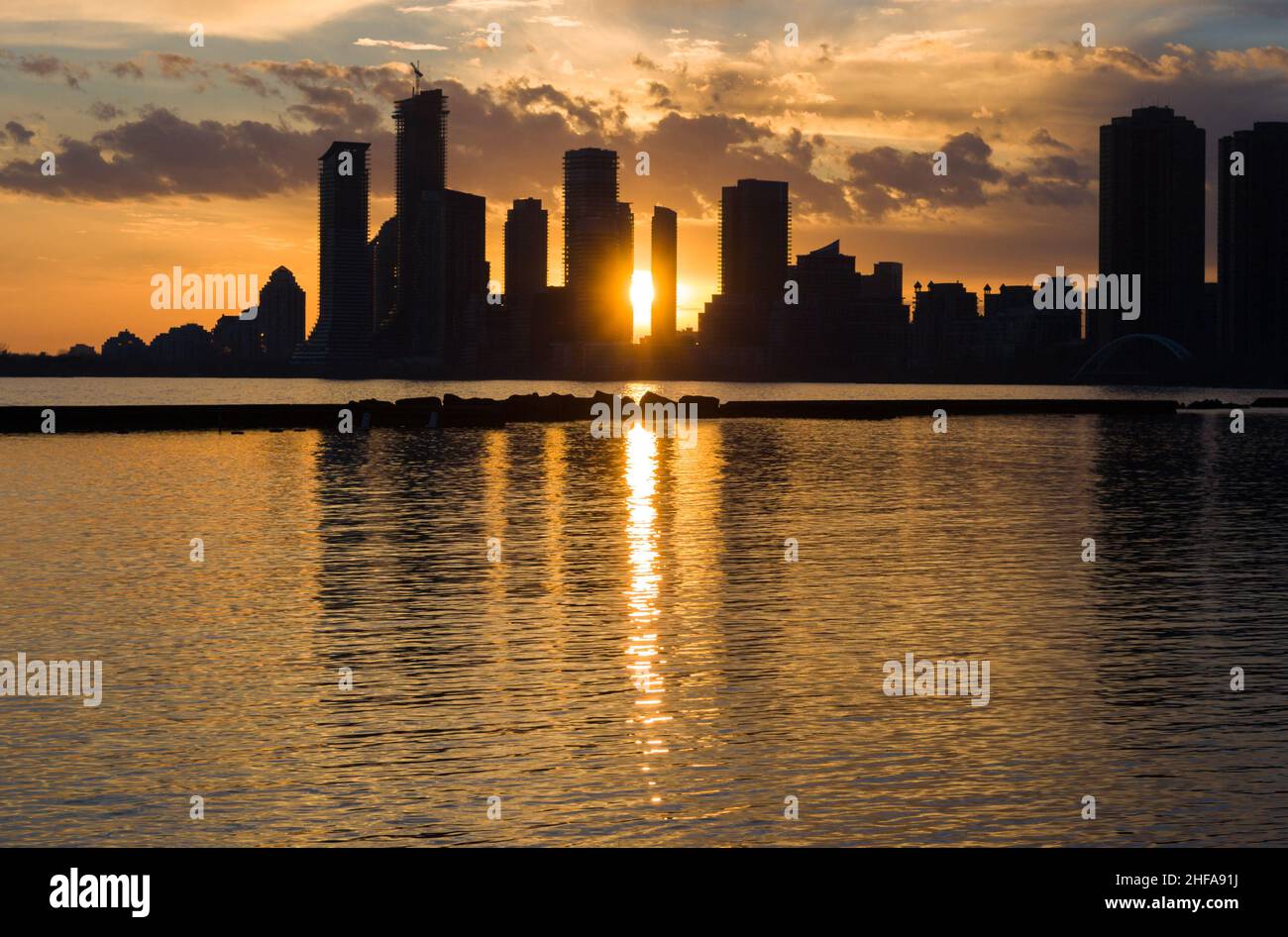 Amazing sunset over sityscape. Cloudy sky with sun rays, lake water ...