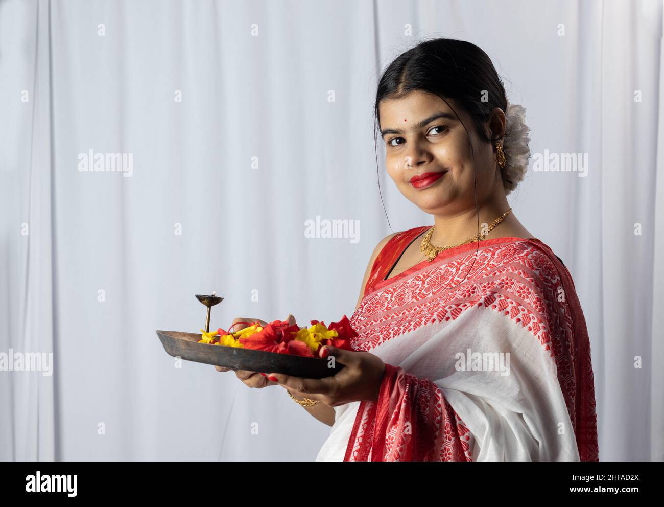 A beautiful Indian woman in red saree holding puja thali or prayer ...