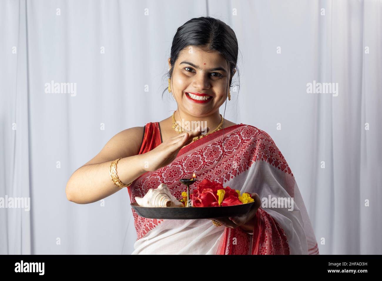 A beautiful Indian woman in red saree holding puja thali or prayer ...