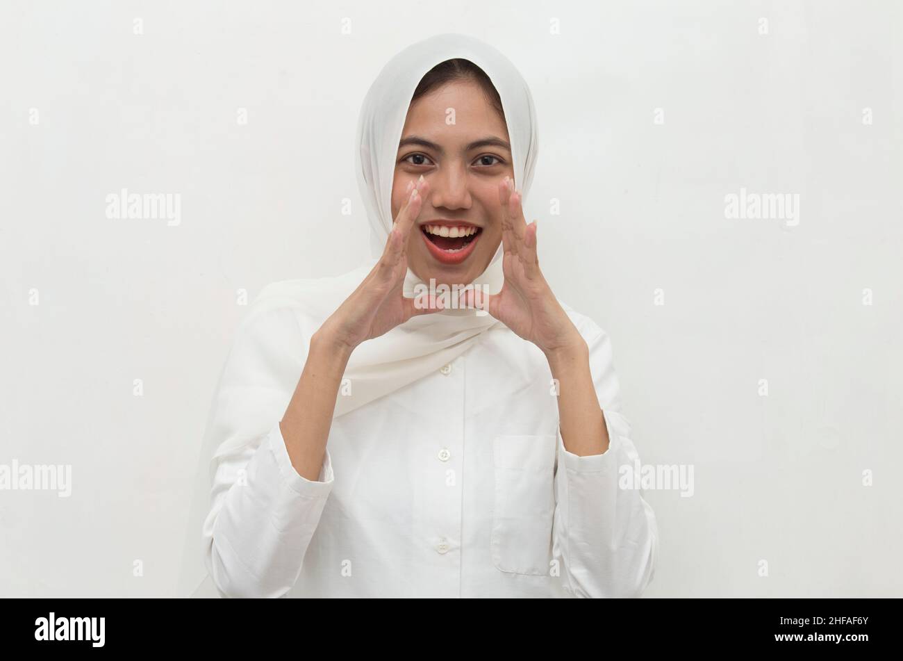 Portrait of young Asian muslim woman wearing hijab shouting and yelling ...