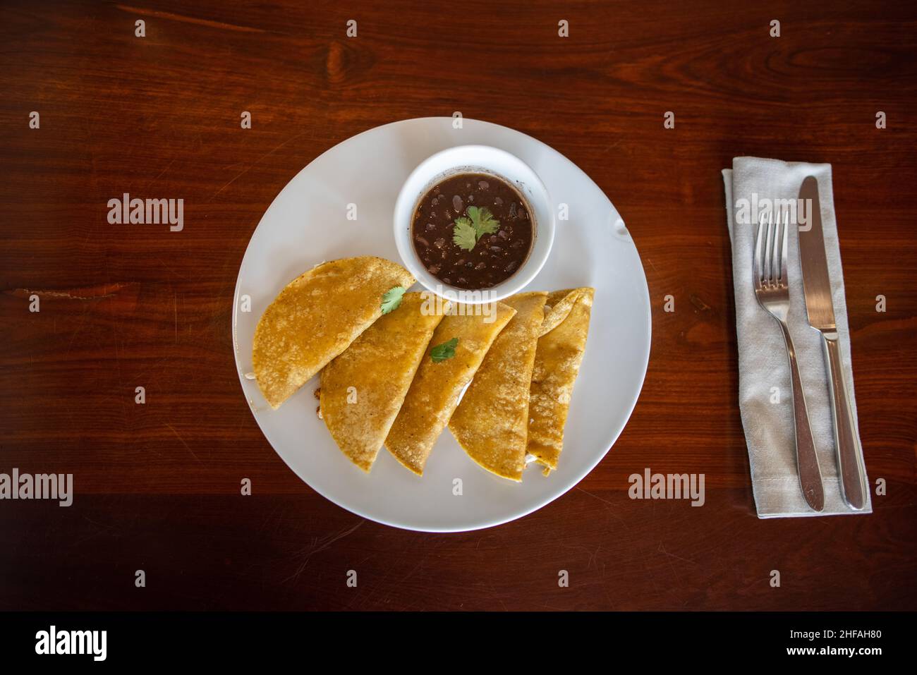 Plate with traditional quesadillas and cup of beans on brown table ...