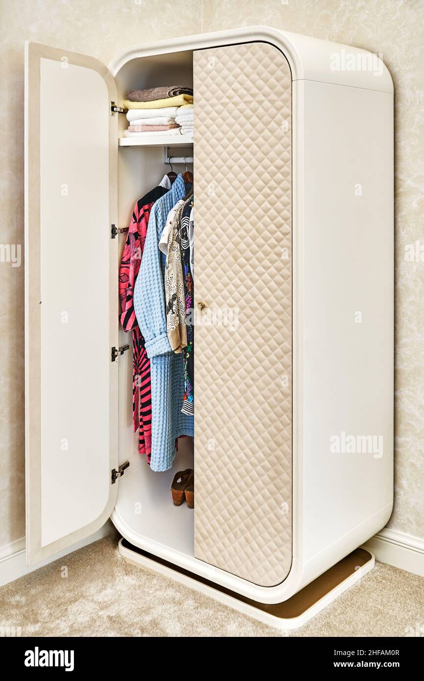 Stylish white wardrobe with different clothes and open door covered ...