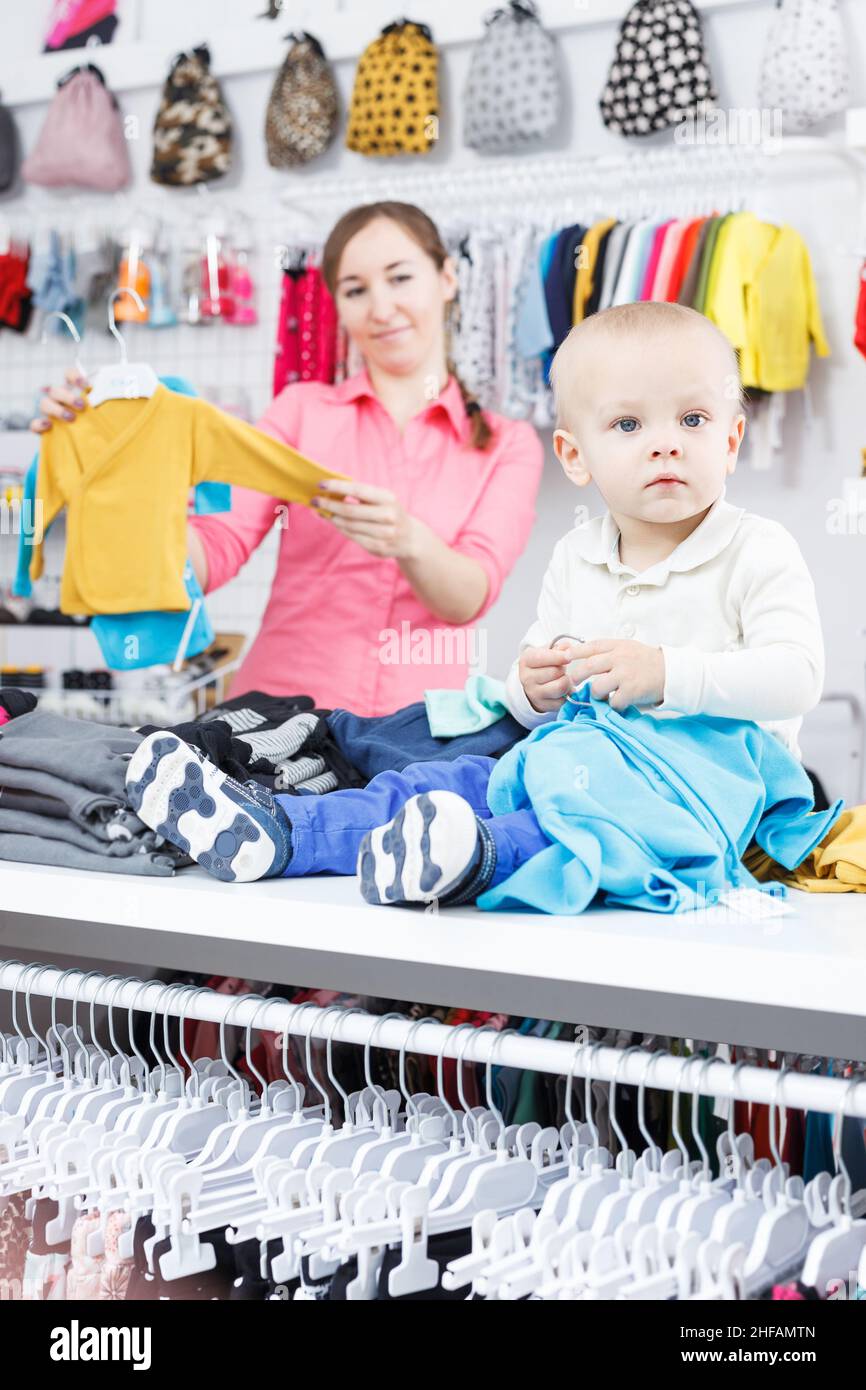 kid who is posing when his mother choosing clothes Stock Photo - Alamy