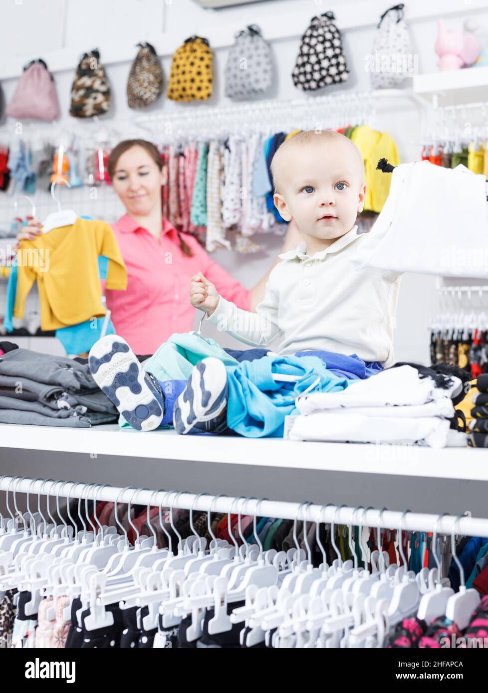 kid who is posing when his mother choosing clothes Stock Photo - Alamy
