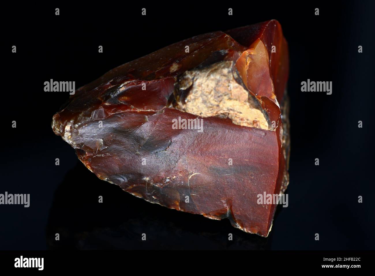 Sample of an untreated red flint with a conchoidal fracture on a dark ...