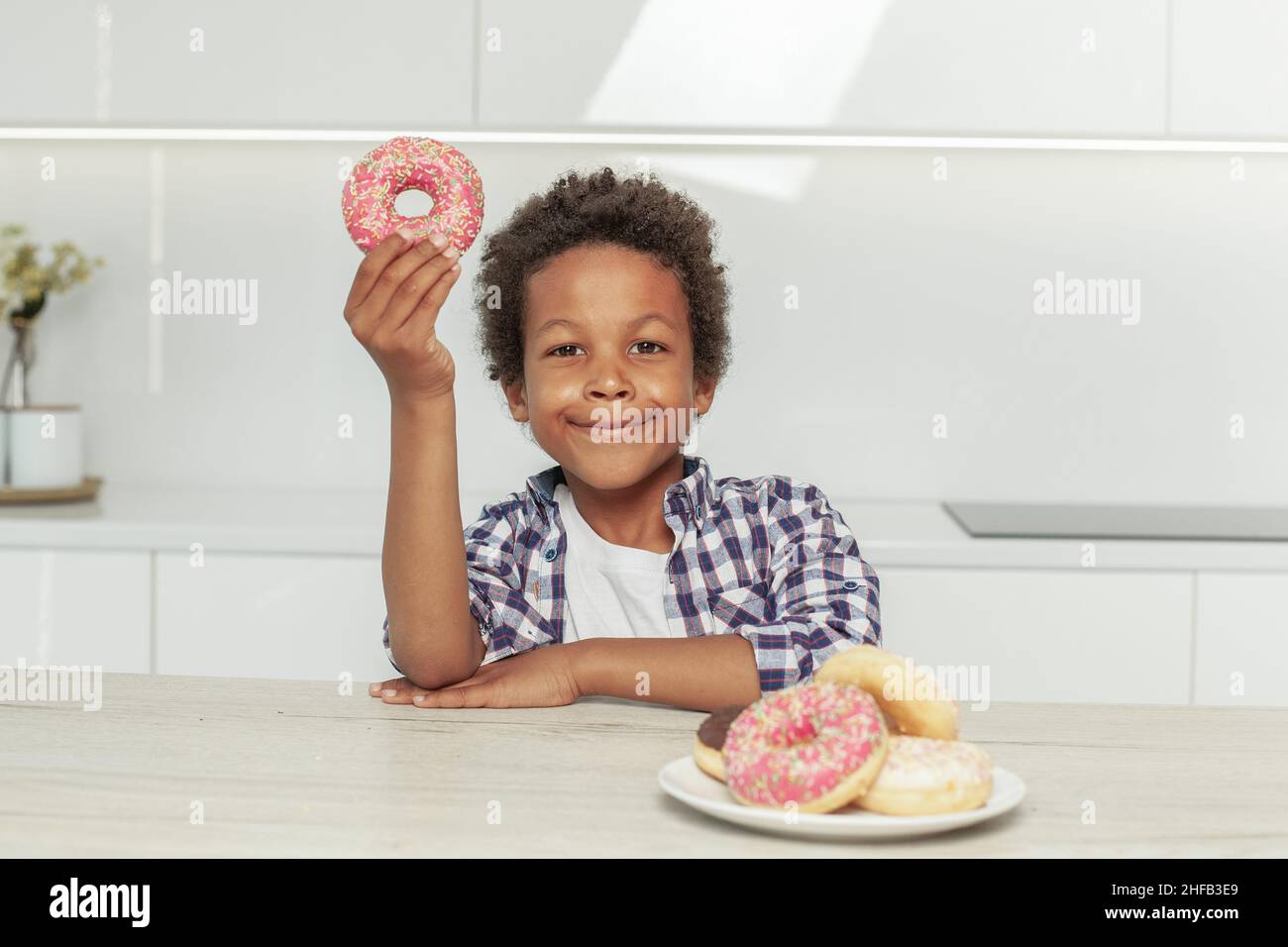 Cute little child and colorful donuts in his hand indoor on white Stock ...