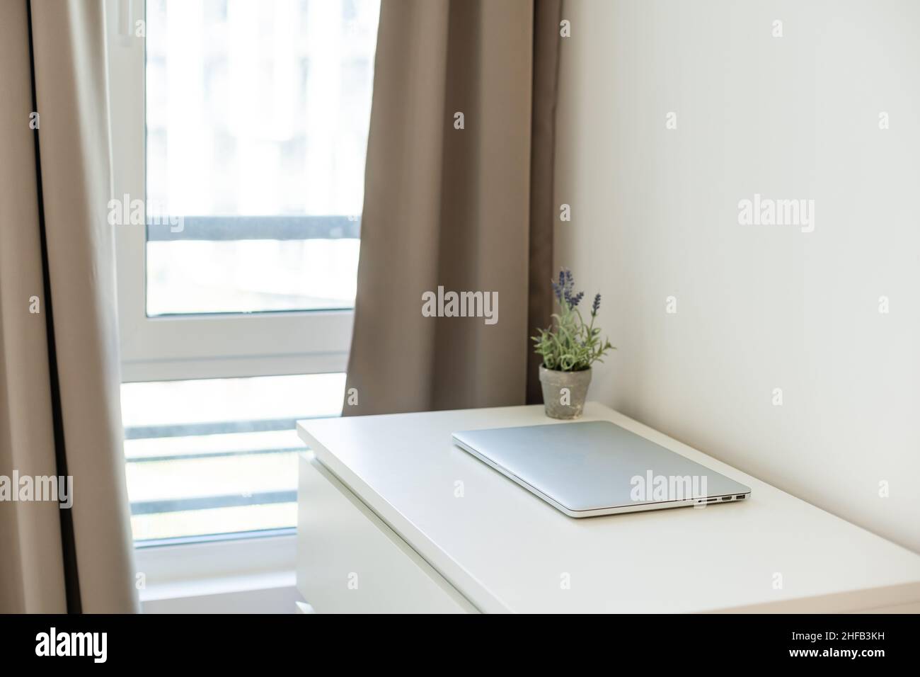 Workspace with laptop closed, on white table with white wall background ...