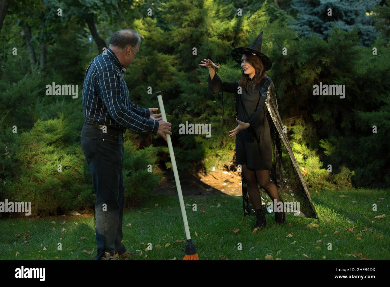 A young beautiful girl in a witch's costume is trying to bewitch a man ...