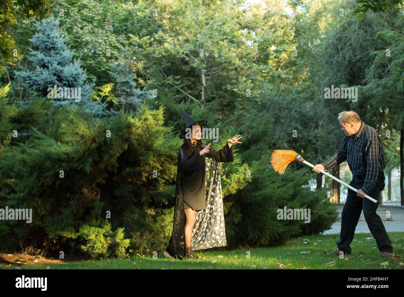 A young beautiful girl in a witch's costume is trying to bewitch a man ...