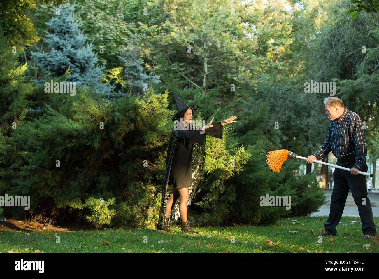 A young beautiful girl in a witch's costume is trying to bewitch a man ...