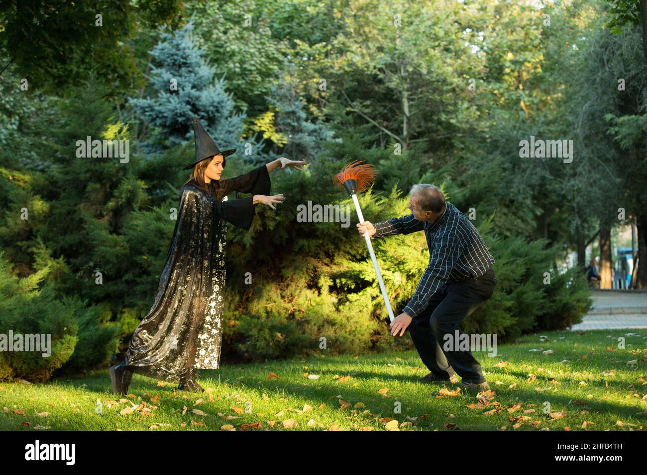 A young beautiful girl in a witch's costume is trying to bewitch a man ...