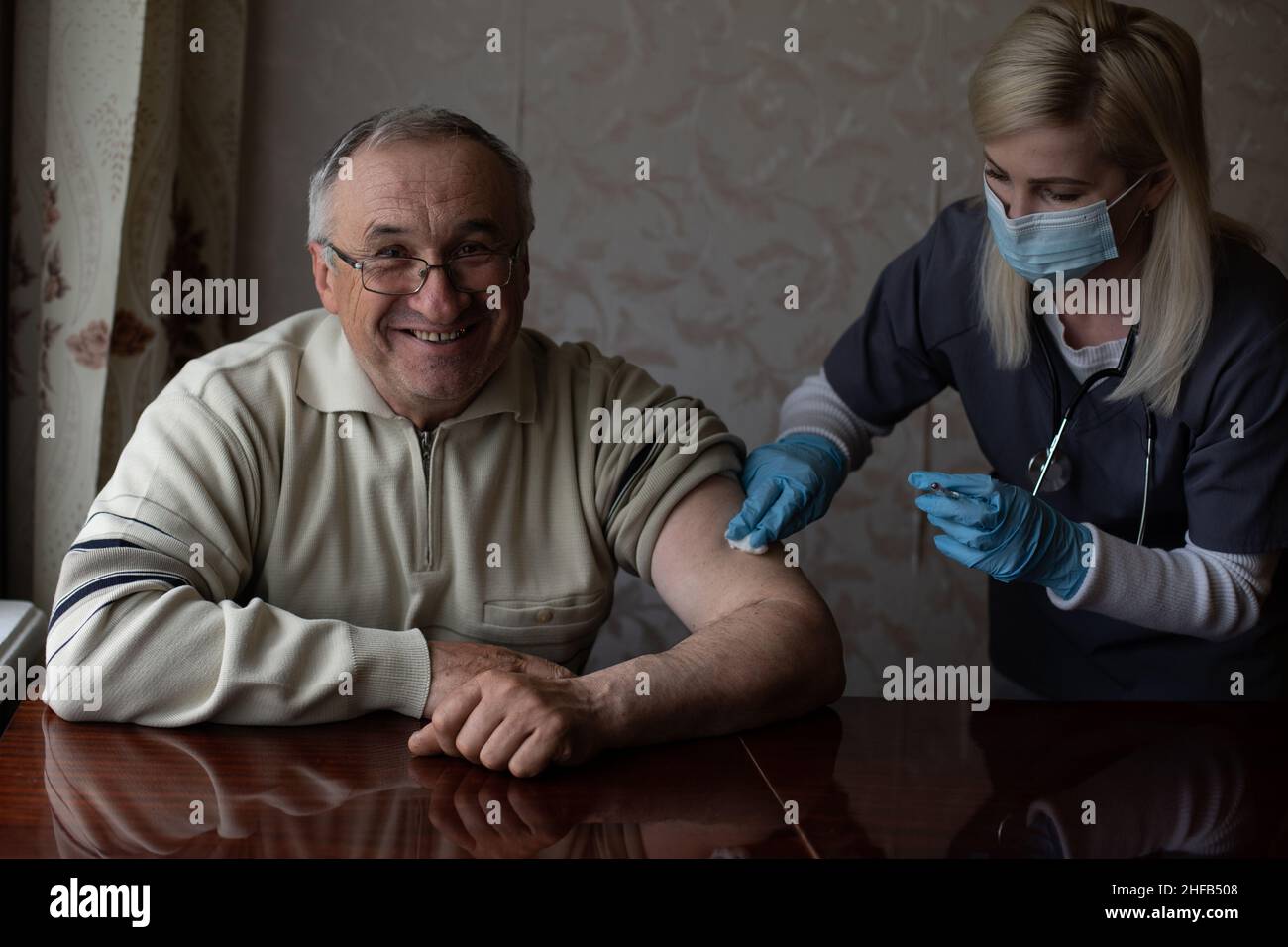 Doctor preparing vaccination shot to elderly patient by holding syringe ...