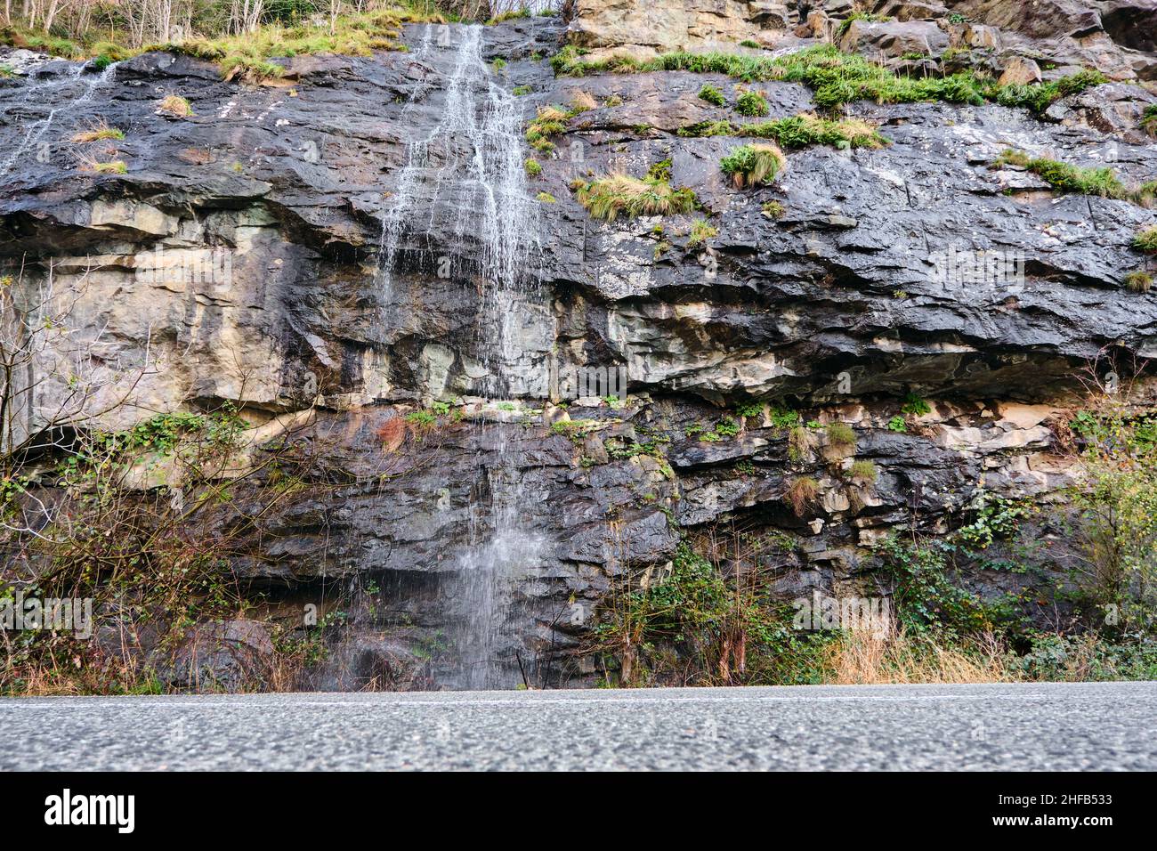 Small waterfall, falling of water behind the stone and rock. Photo ...