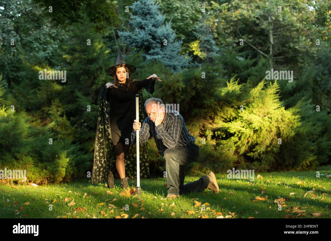 A young beautiful girl in a witch's costume is trying to bewitch a man ...