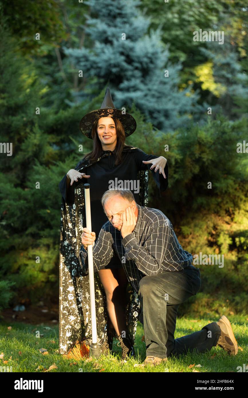 A young beautiful girl in a witch's costume is trying to bewitch a man ...