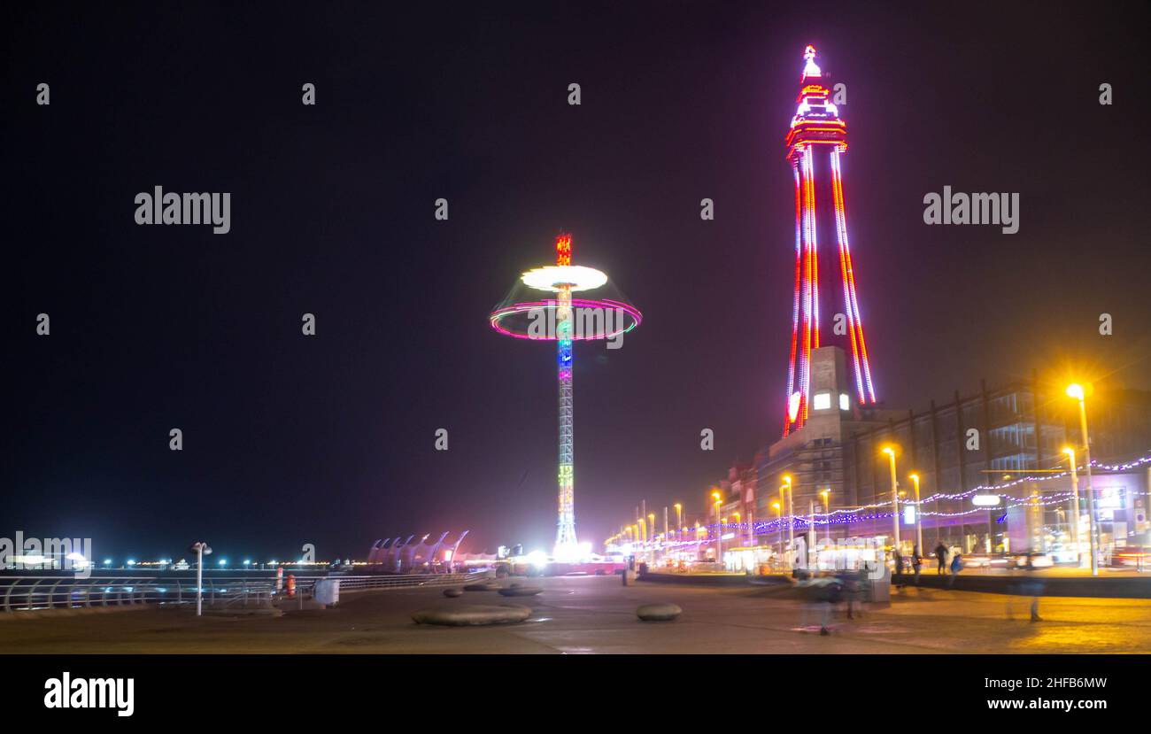 Blackpool Tower with a spinning funfair ride lit up with the ...