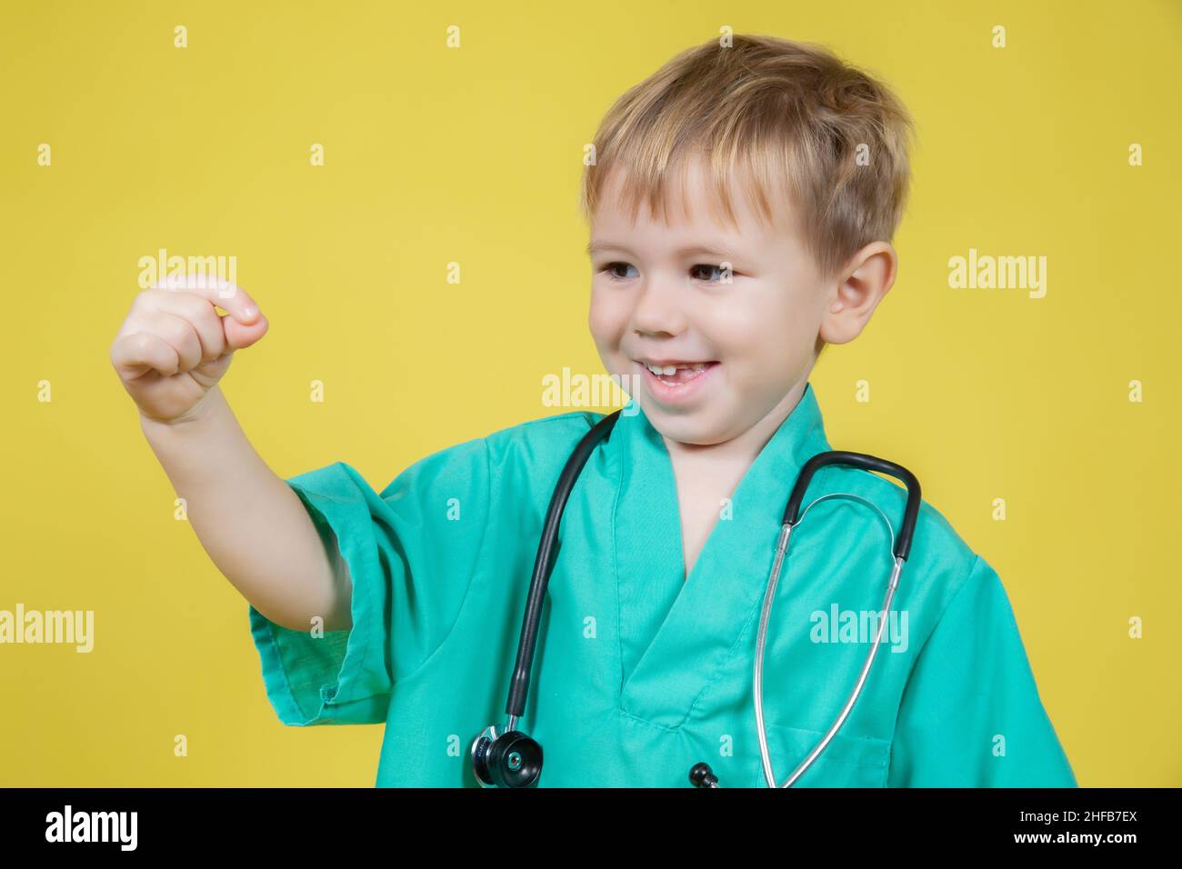 Portrait of cute little caucasian kid dressed in doctors green showing ...
