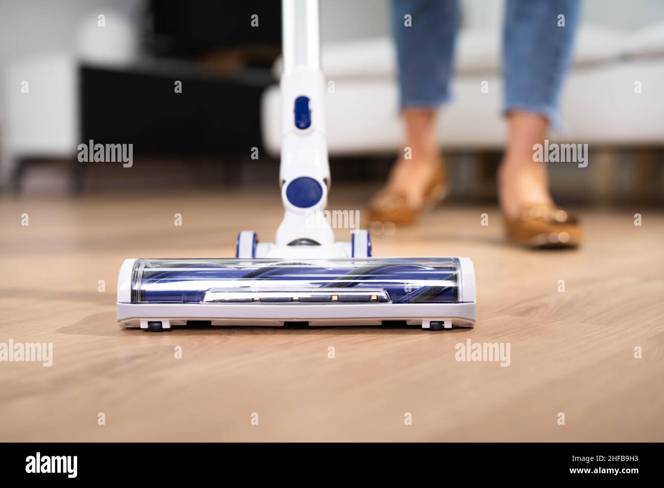 Young Maid Cleaning Floor With Handheld Vacuum Cleaner Stock Photo - Alamy