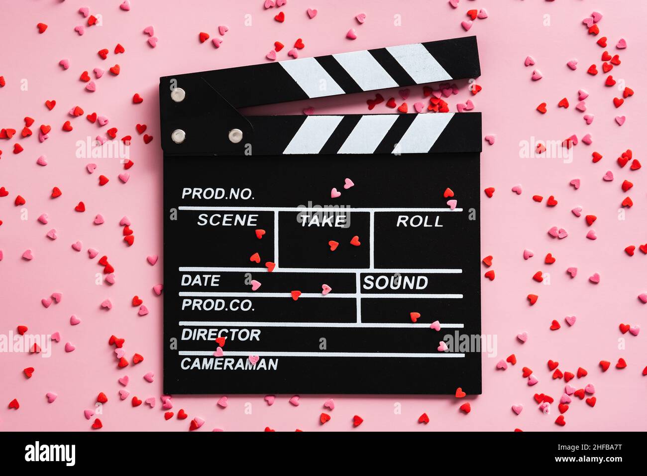 Movie clapper board and confetti on pink background. Romantic movie ...