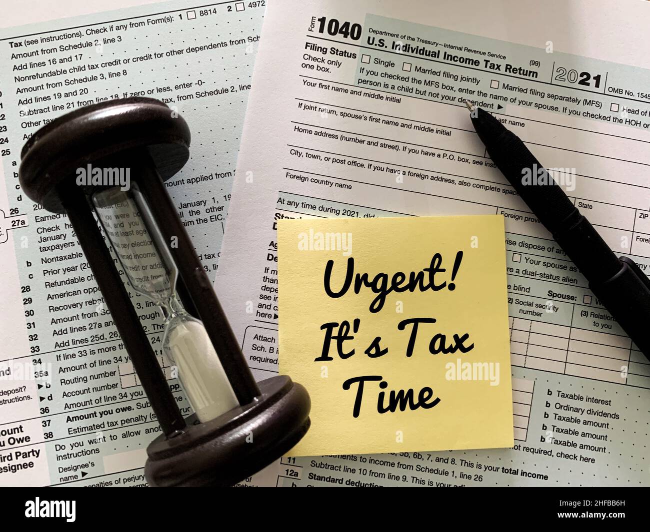 It's tax time on sticky note with 1040 tax form, pen and minutes glass ...