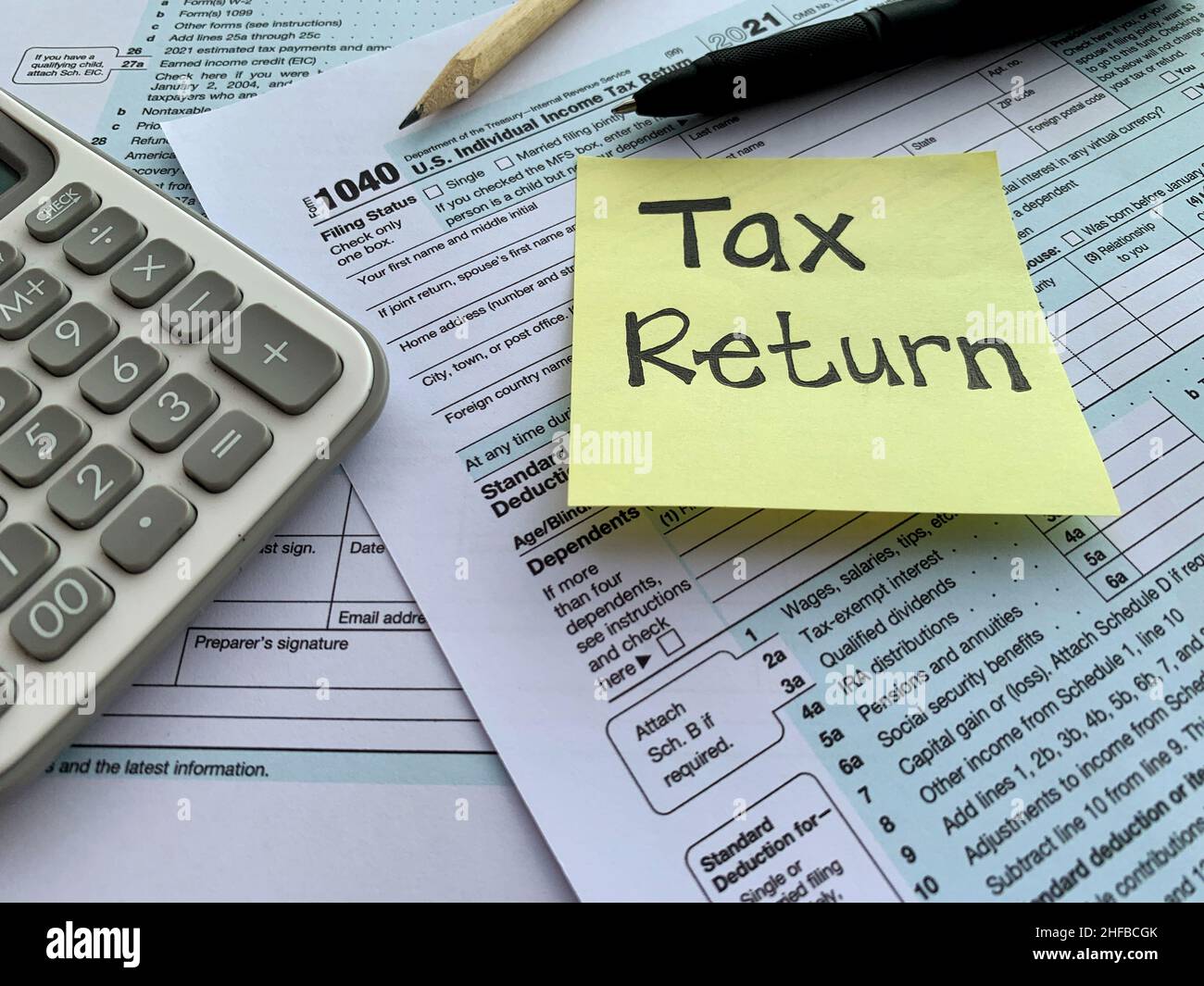 Close up on hand written tax return on sticky note with 1040 tax form ...