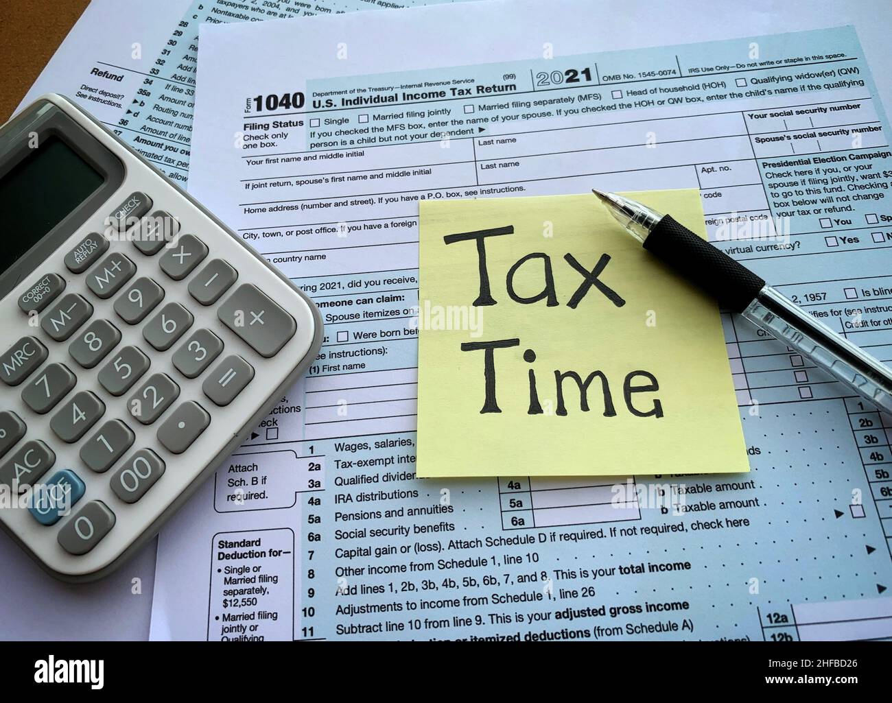 Close up on tax time text on sticky note with 1040 tax form, pen and ...