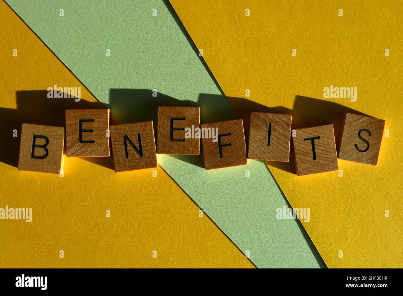 Benefits, word in wooden alphabet letters isolated on yellow and green ...