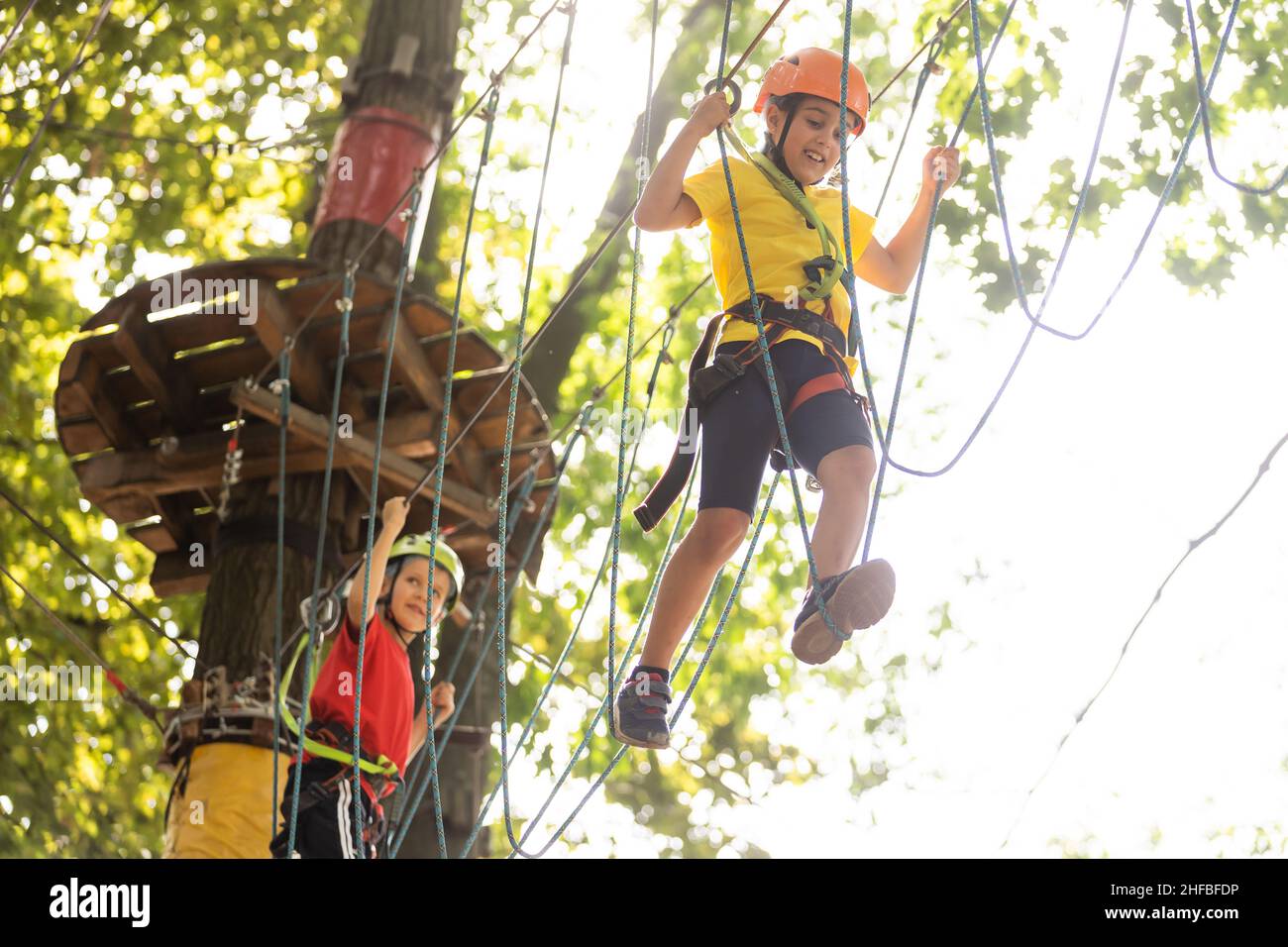 Child in forest adventure park. Kids climb on high rope trail. Agility ...