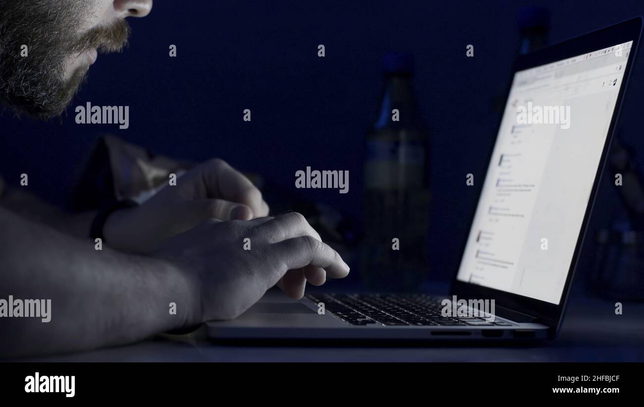 Man with a beard working late at night on the computer. Young man ...
