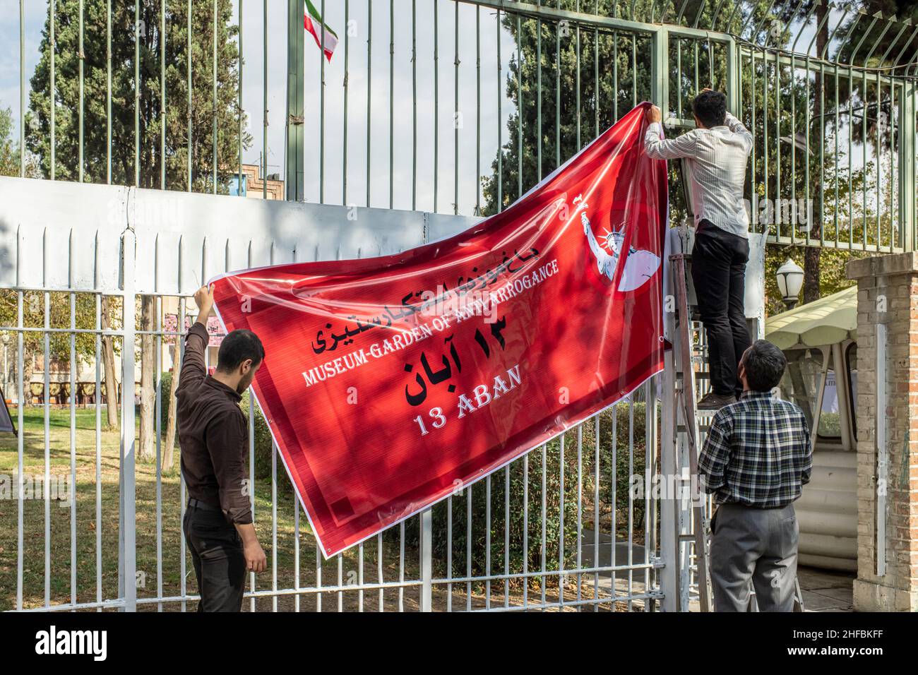 Raising a banner commemorating the takeover of the US Embassy in Tehran ...