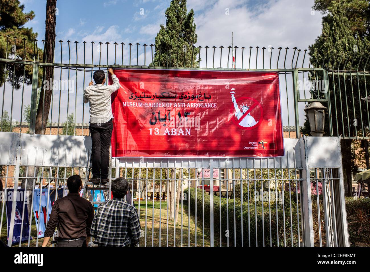 Raising a banner commemorating the takeover of the US Embassy in Tehran ...