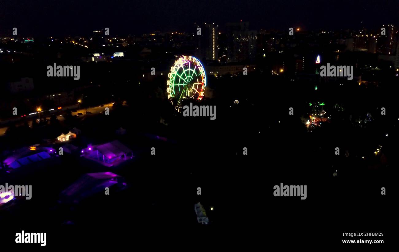 Aerial night view of city skyline and ferris wheel. Top view of Ferris ...