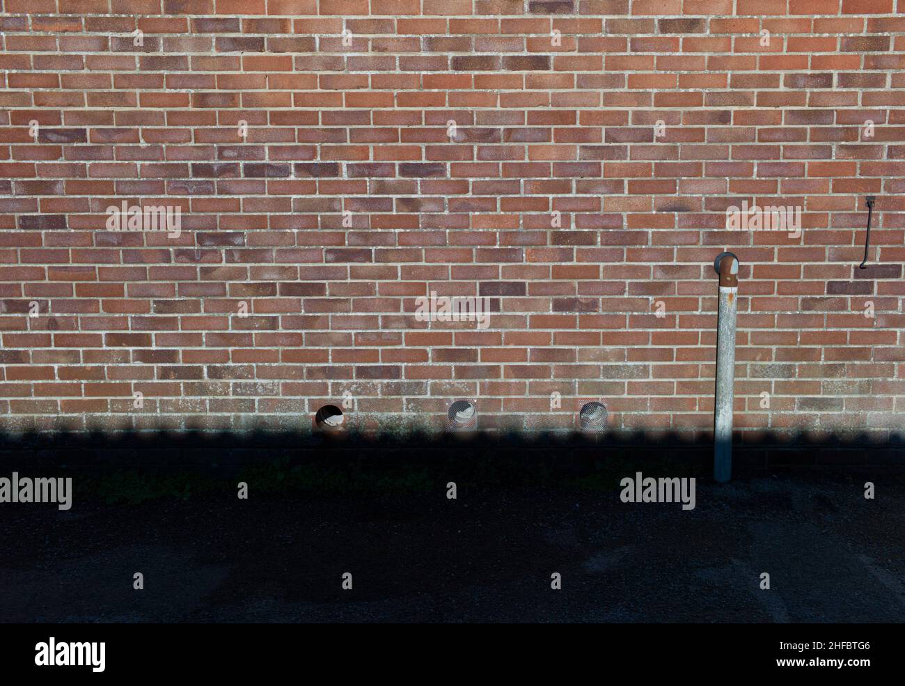 A brick wall with pipe, hook, ventilation holes and shadow Stock Photo ...
