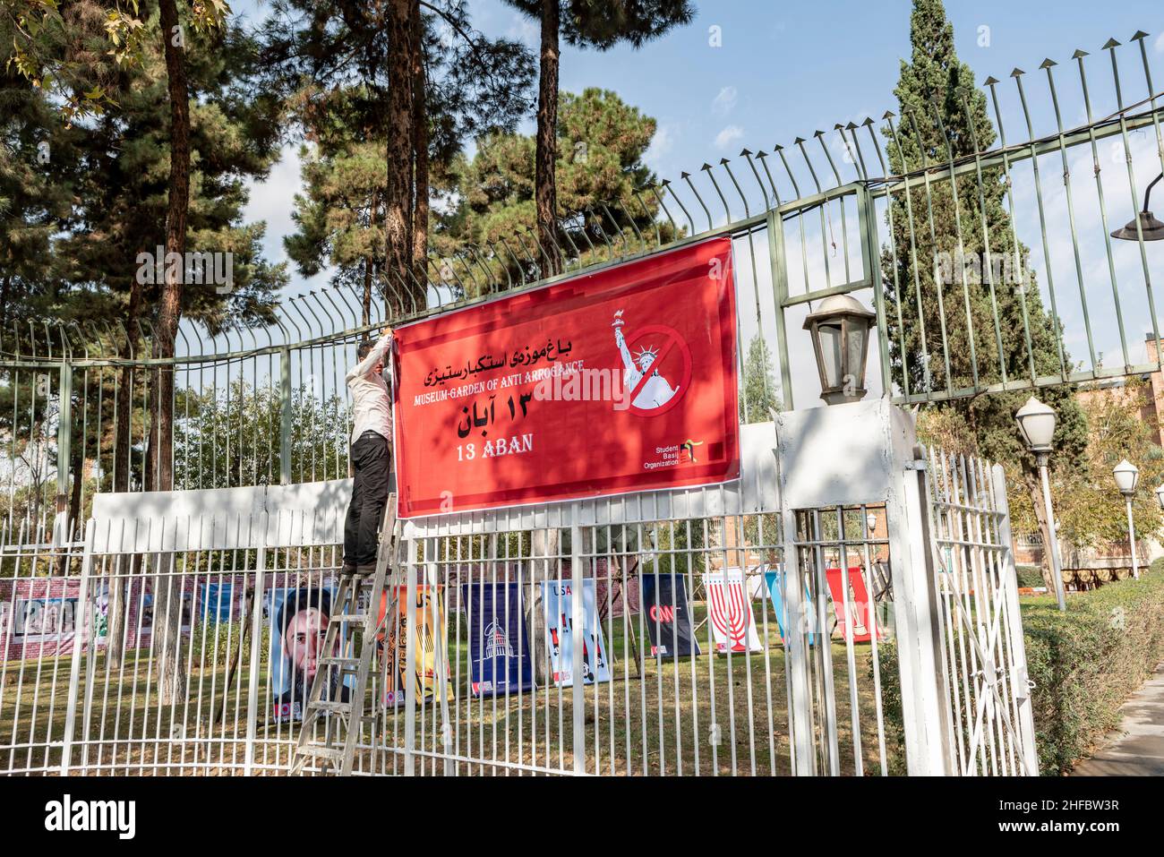 Raising a banner commemorating the takeover of the US Embassy in Tehran ...