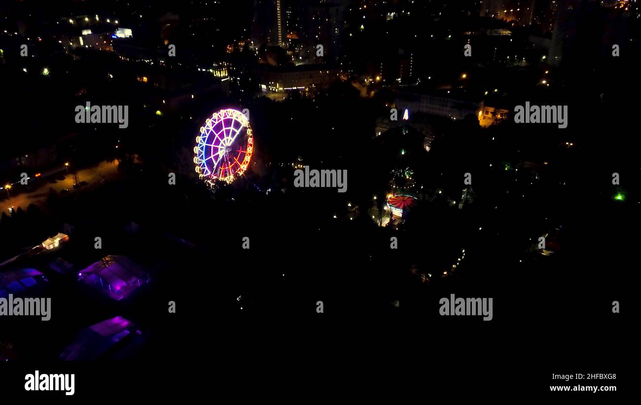 Aerial night view of city skyline and ferris wheel. Top view of Ferris ...