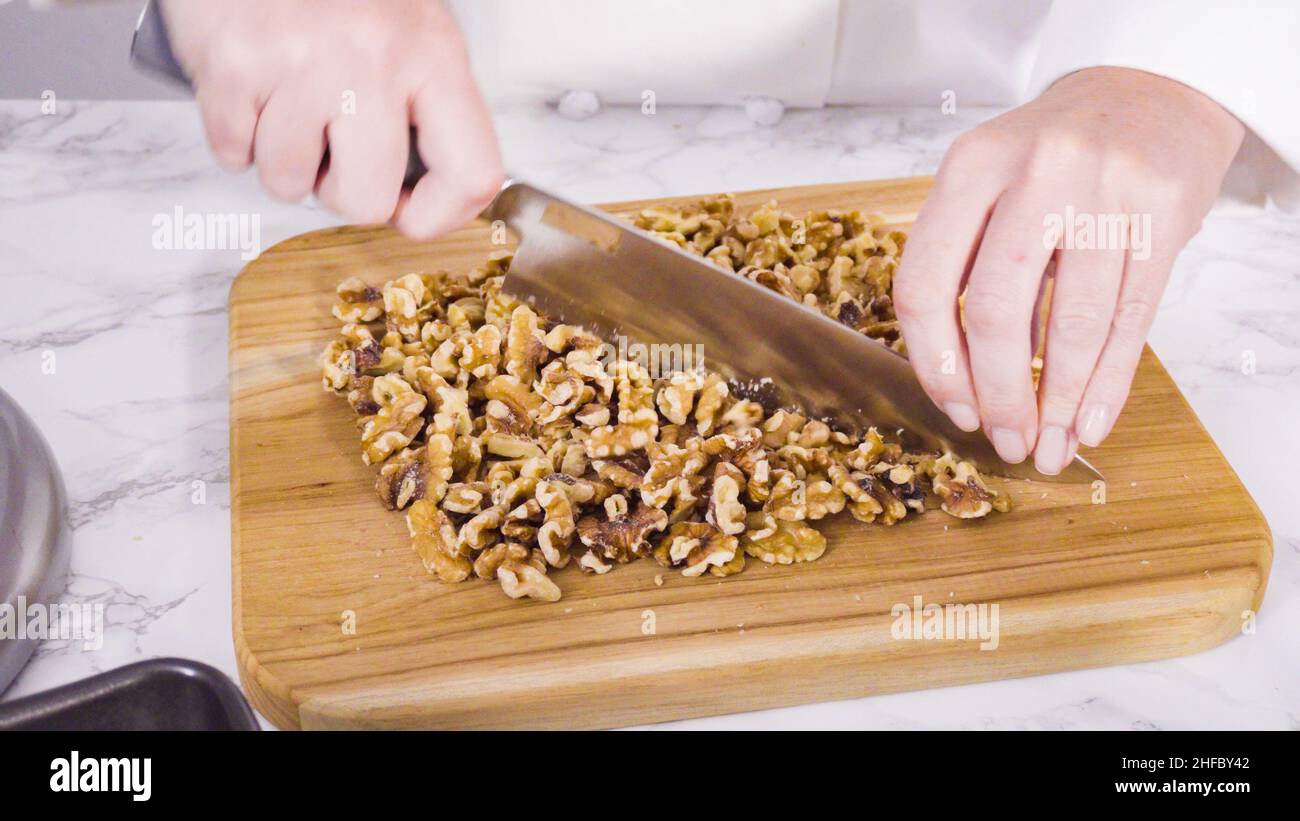 Step by step. Chopping walnuts with kitchen knife on a wood cutting ...