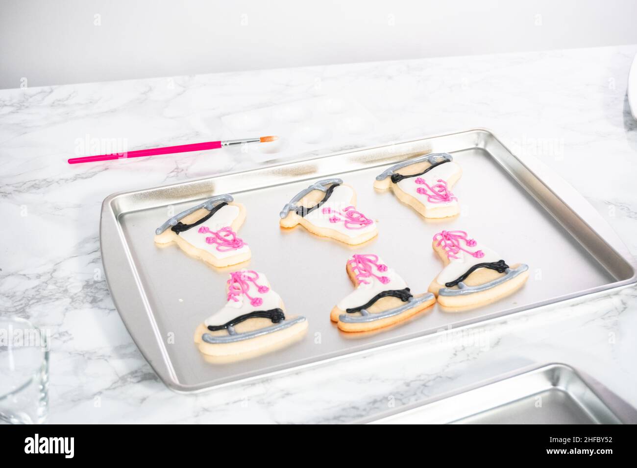 Decorating sugar cookies shaped as figure skates with royal icing Stock ...