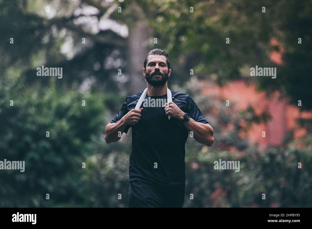 Determined young man running outside in the park. Fit boy doing ...