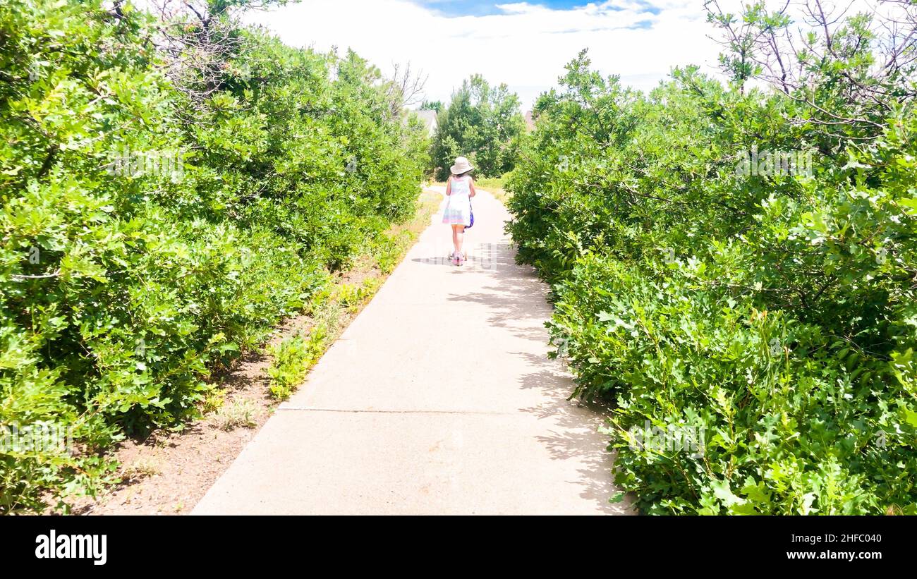 Little girl riding the scooter on suburban trail in the Summer Stock ...