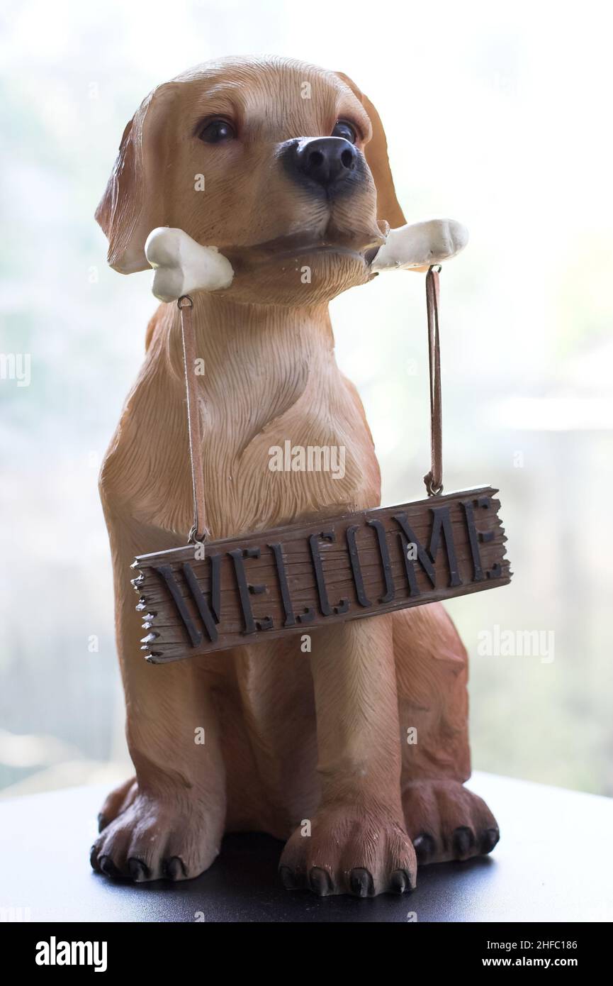 Dog holding a bone on which hangs a sign saying Welcome Stock Photo - Alamy